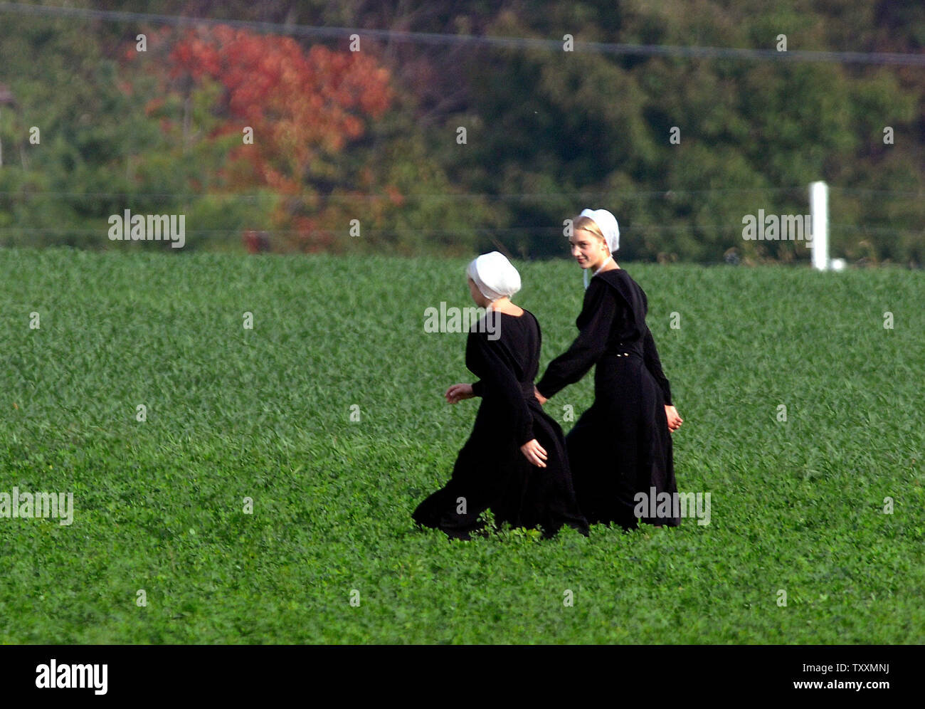 Two Amish young women cross a field near the Nickel Mines School House ...