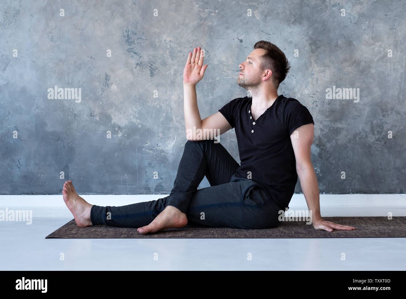 Young man sitting twisted on floor, stretching back, Side view Stock ...