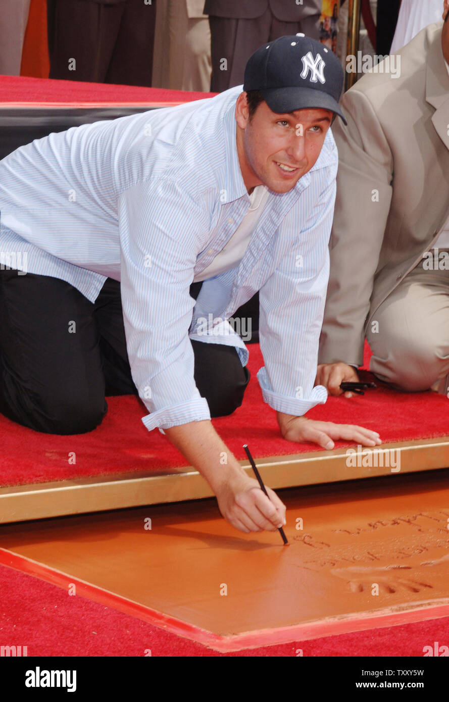 Actor Adam Sandler signs his name in wet cement during a hand and ...