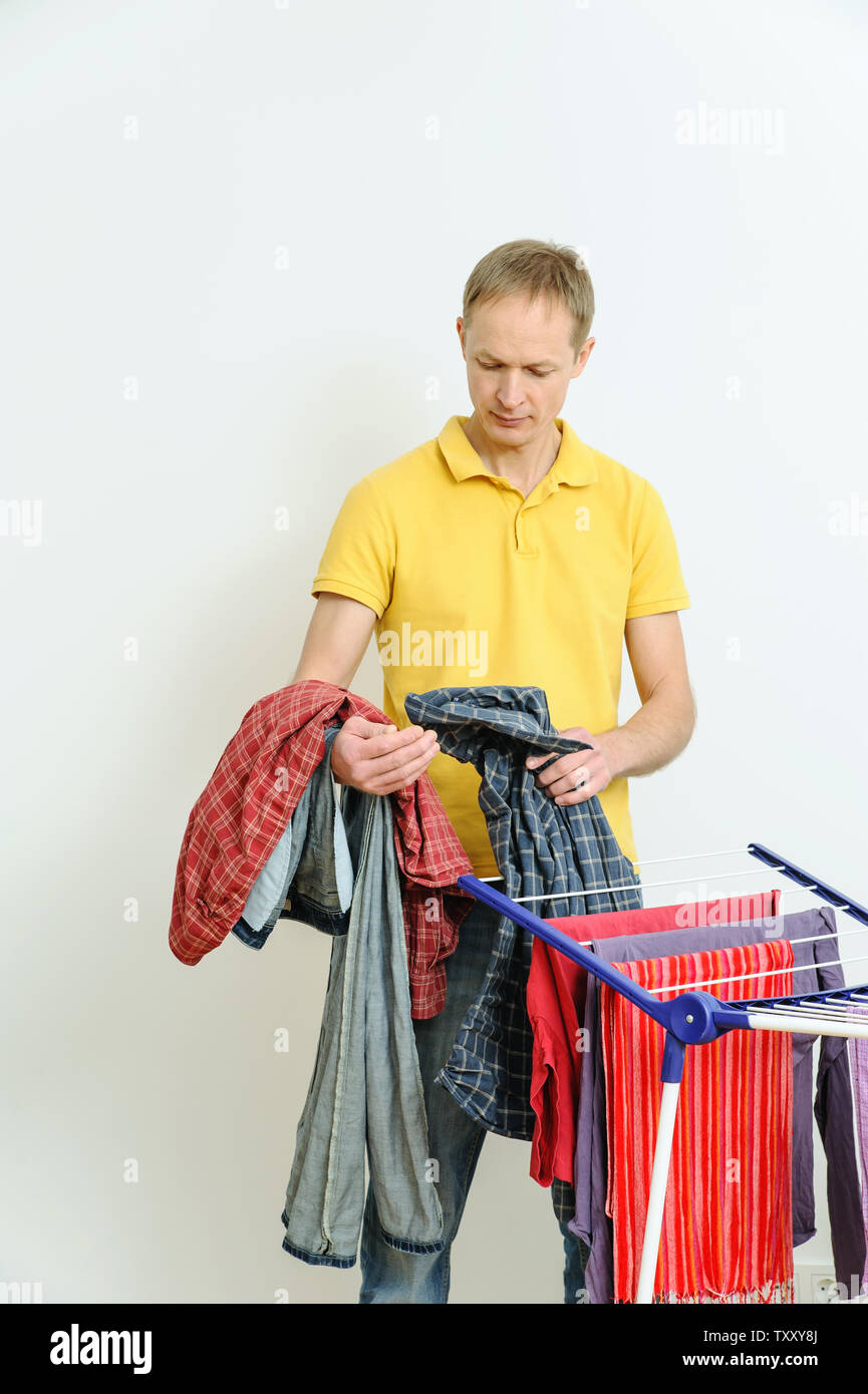 The man takes off things from drying rack clothes Stock Photo - Alamy