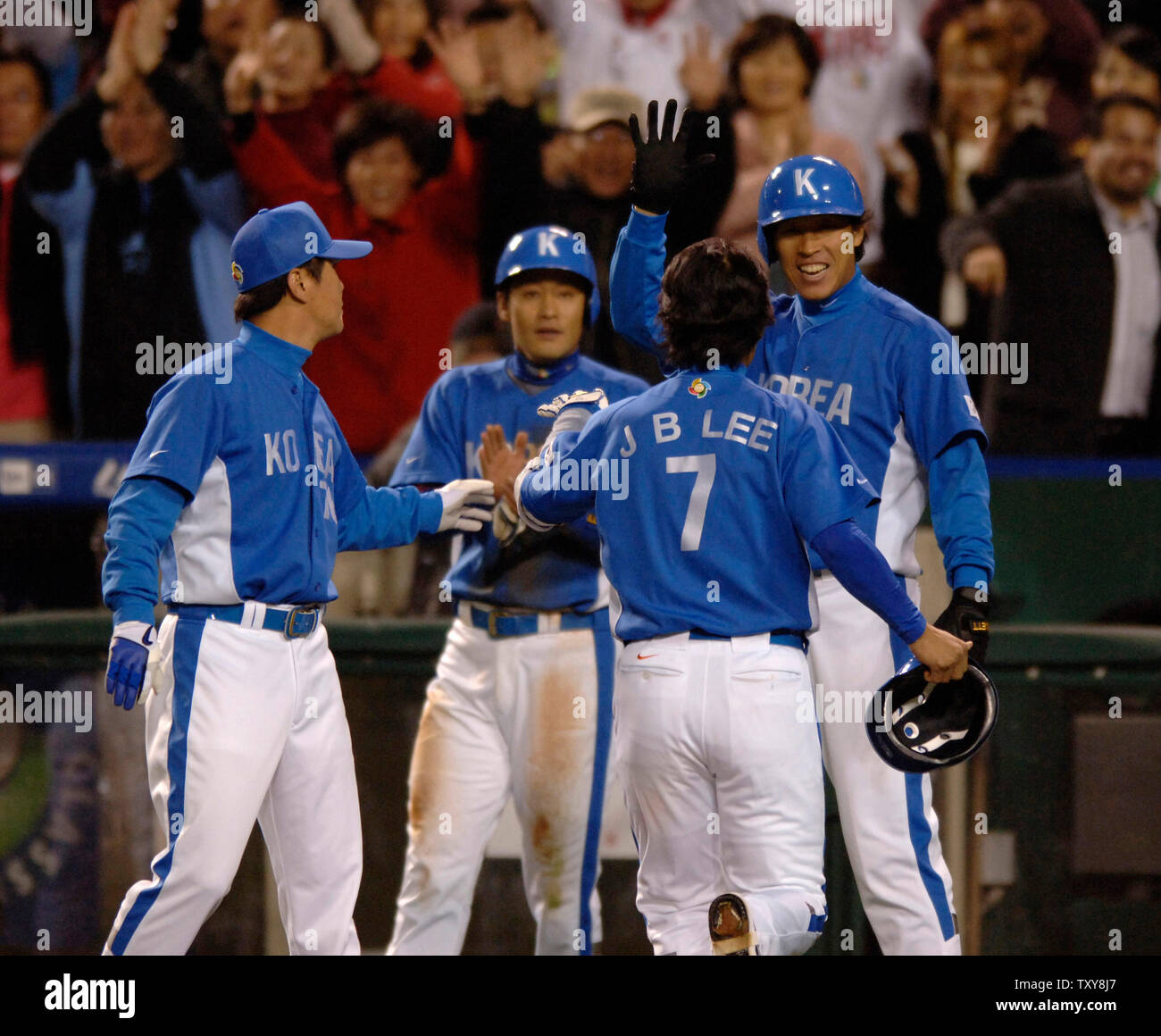 Korea #7 Jong Beom Lee is congratulated as he returns to the dugout ...