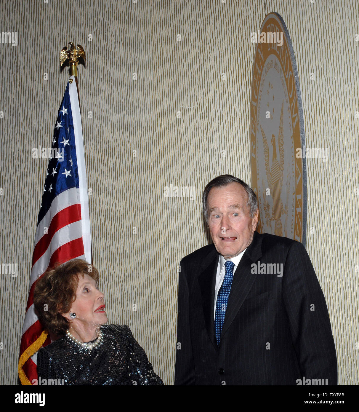 Former President George H.W. Bush (R) reacts as the event logo swings ...