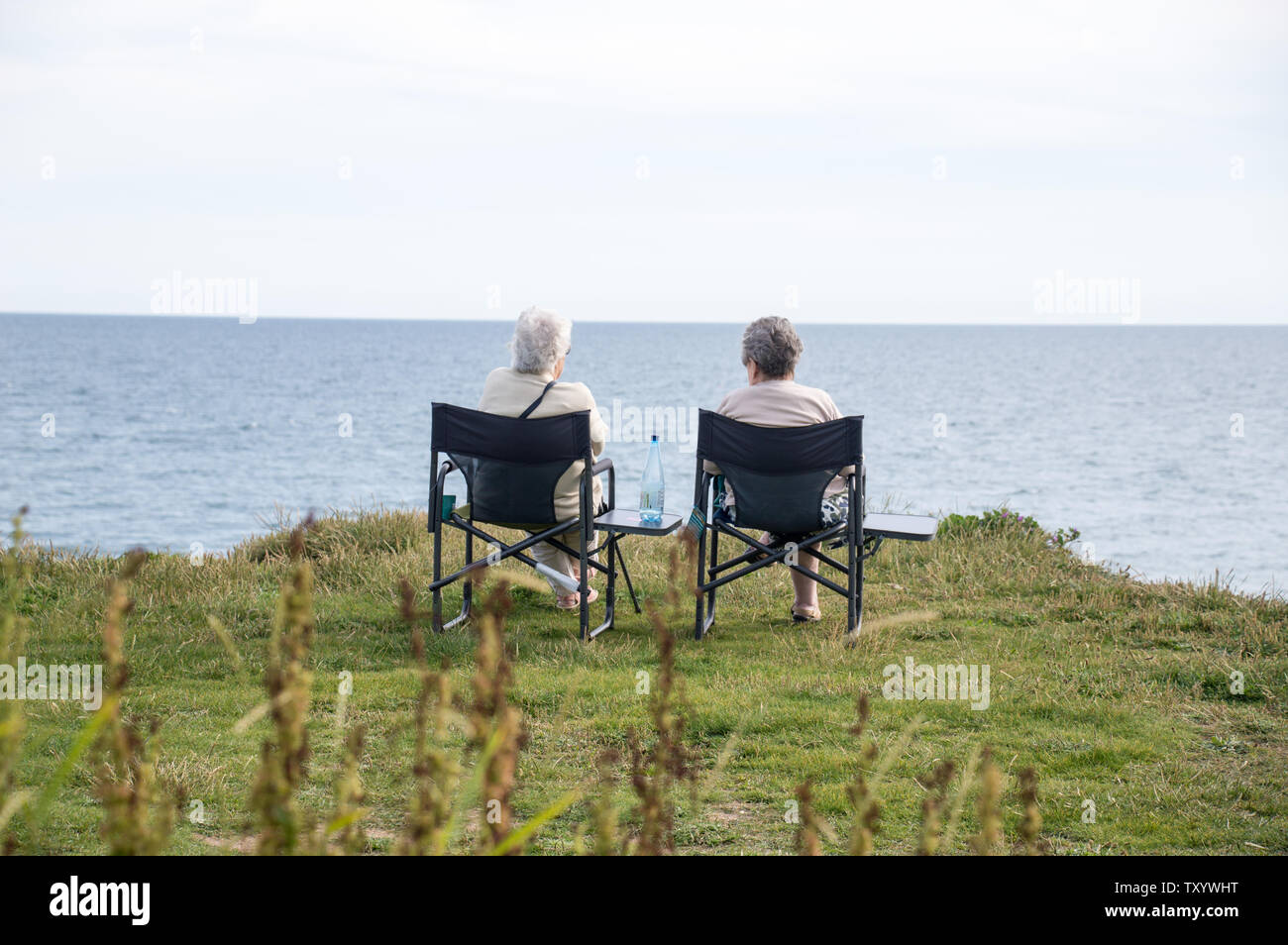 Rear View Of Two Old Ladies Enjoying The Sea View On A Sunny Afternoon