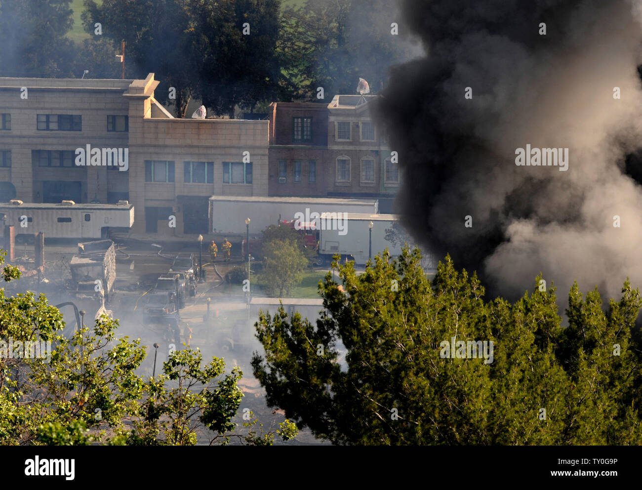Firefighters on aerial ladders spray water on a fire as it rages out of ...