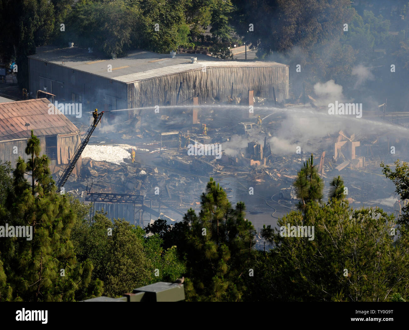 Firefighters on aerial ladders spray water on a fire as it rages out of ...