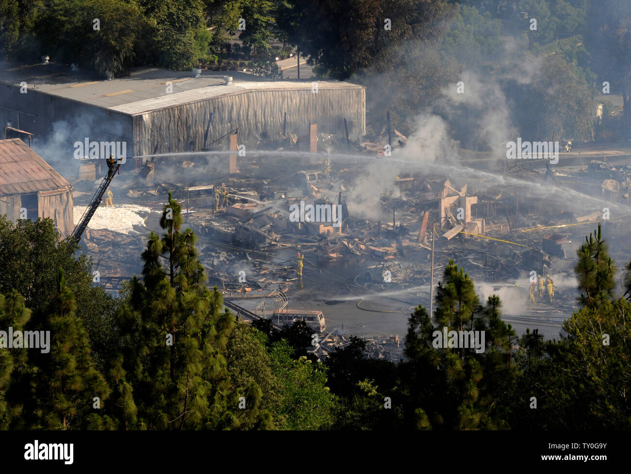 Firefighters on aerial ladders spray water on a fire as it rages out of ...