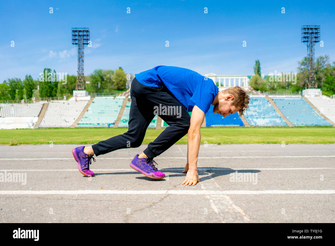 young runner athlete in the low start position on the sports track on ...