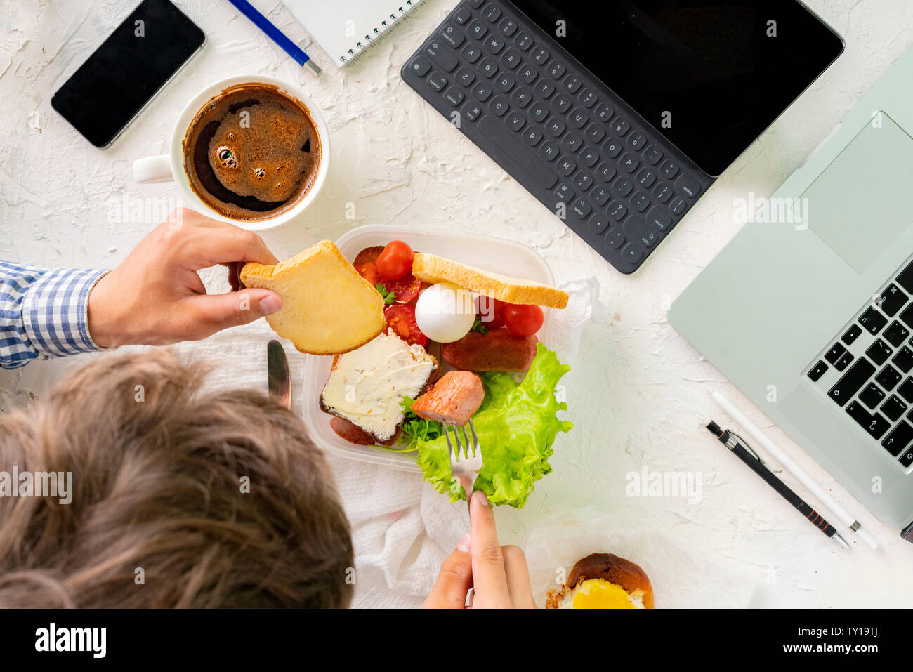 young male taking meal in front of the laptop while working, bad habit ...