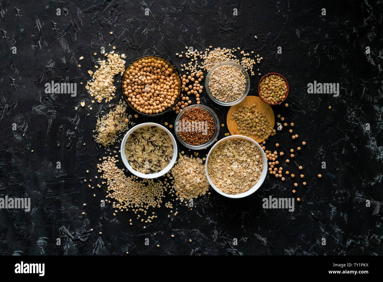 selection of raw uncooked cereals grains in bulbs with chickpeas oat ...