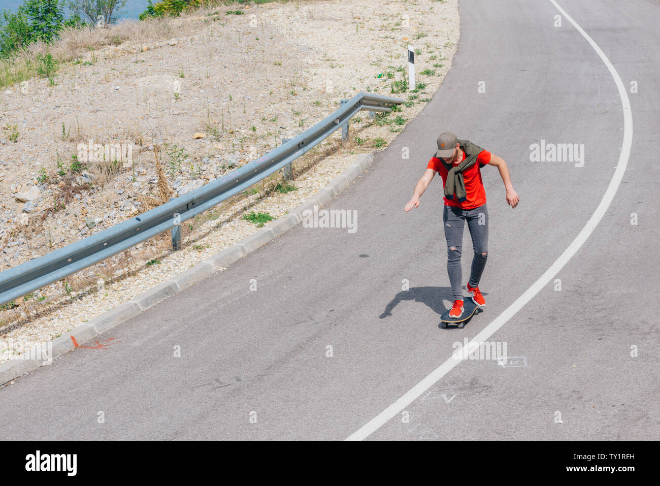 Male caucasian longboarder riding downhill on an empty road, preparing ...