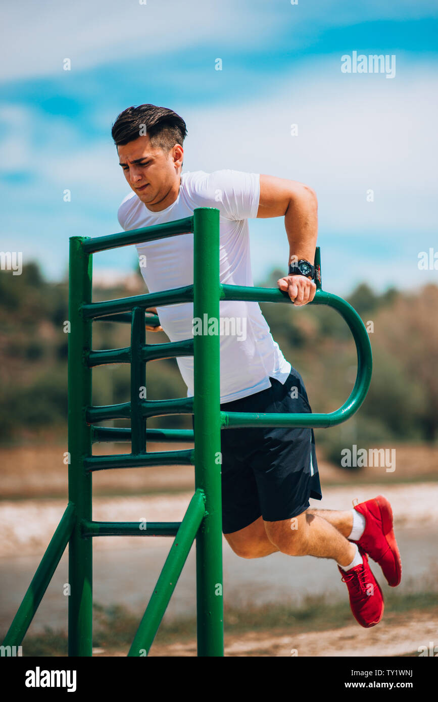 Fit man workout out arms on dips horizontal bars training triceps and ...