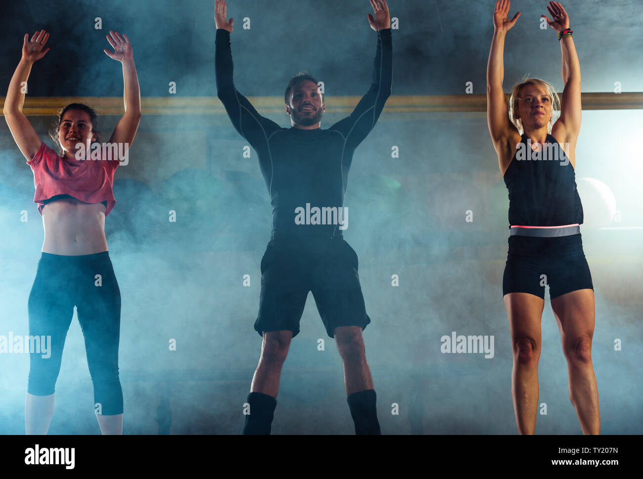 Happy and smiling crossfit workout group jumping together in crossfit ...