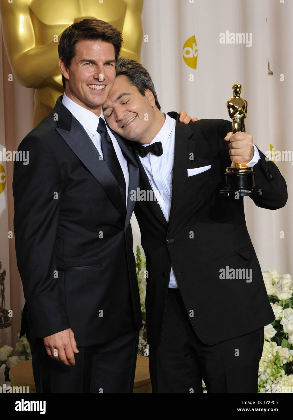 Producer Thomas Langmann leans into actor Tom Cruise while holding the ...