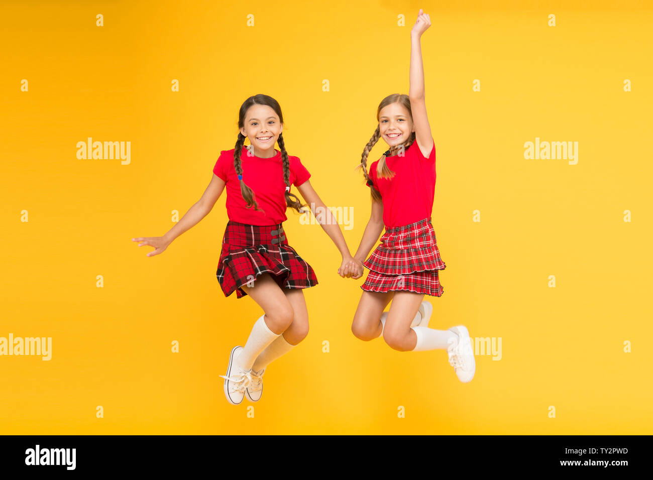 Scottish style. Cheerful friends schoolgirls jumping yellow background ...