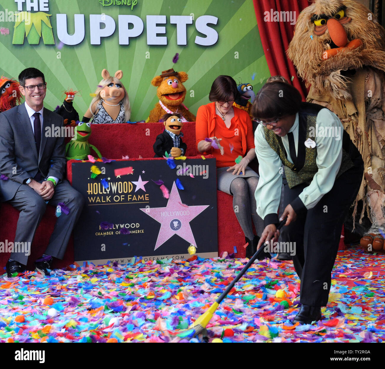 Walt Disney Studios President Rich Ross,looks on as a woman sweeps ...