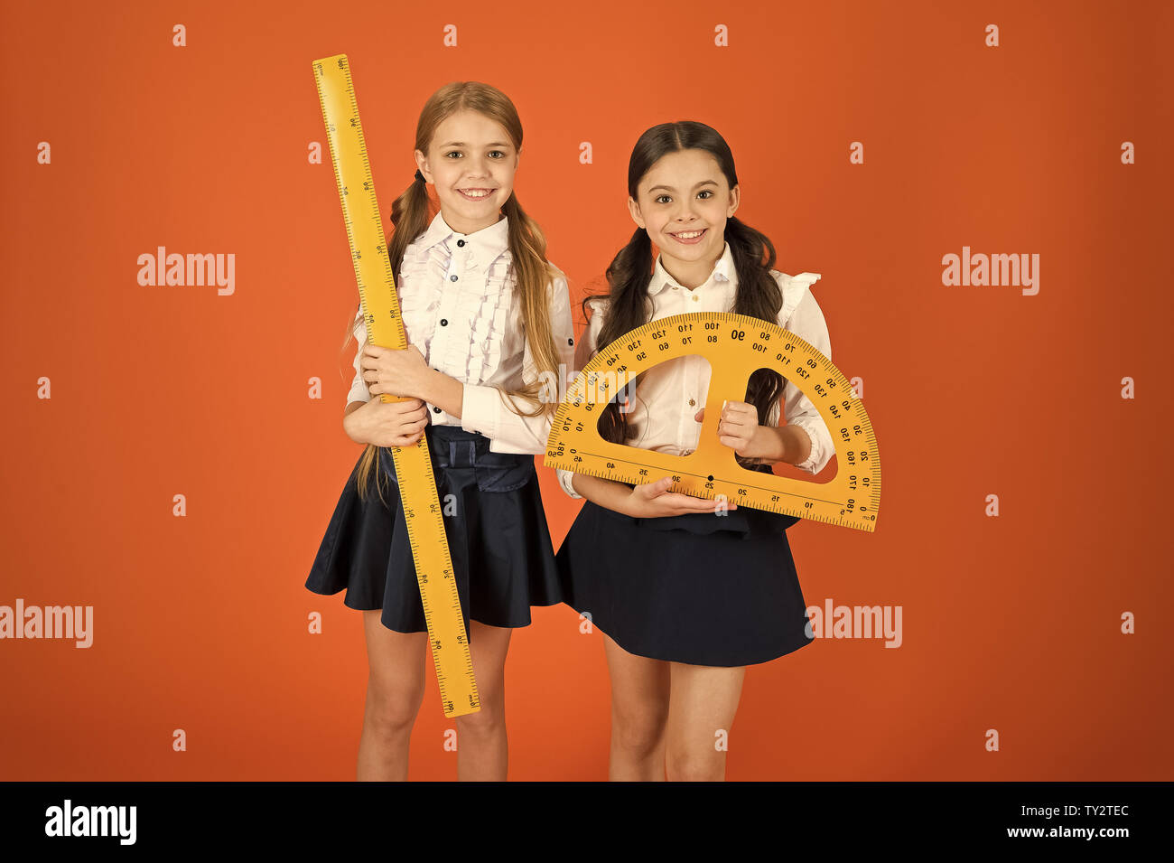 Having a private lesson. Cute schoolgirls holding protractor and ruler ...