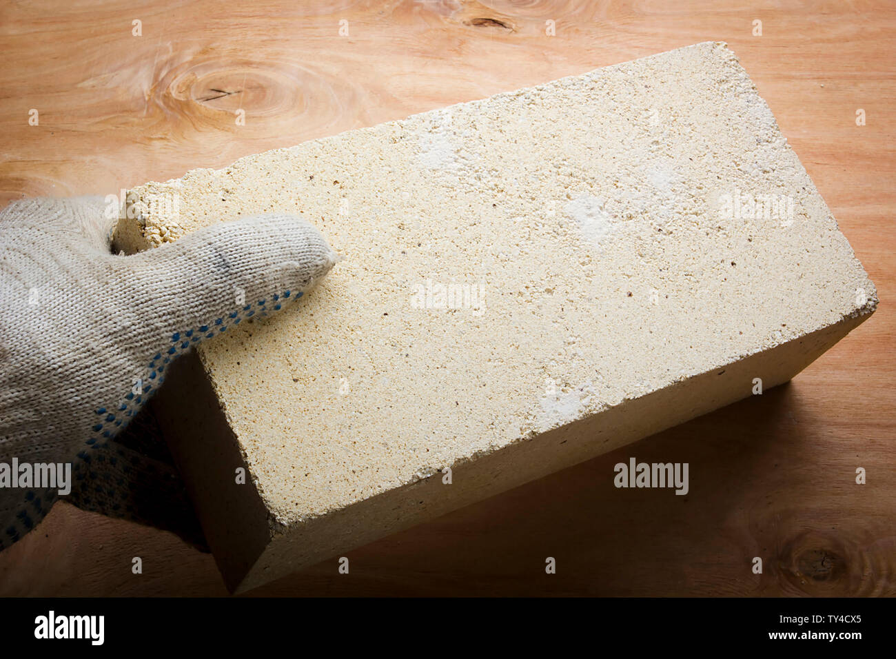 Hand in a working glove holds a brick Stock Photo - Alamy