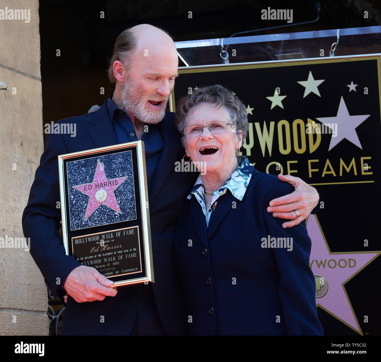 Actor Ed Harris holds a replica plaque while he hugs his mother ...