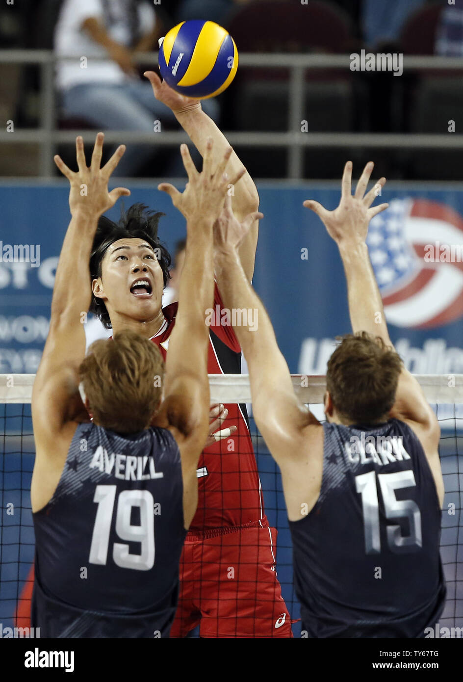Japan's Kunihiro Shimizu, center, hits against USA's Taylor Averill (19) and Carson Clark (15 ...