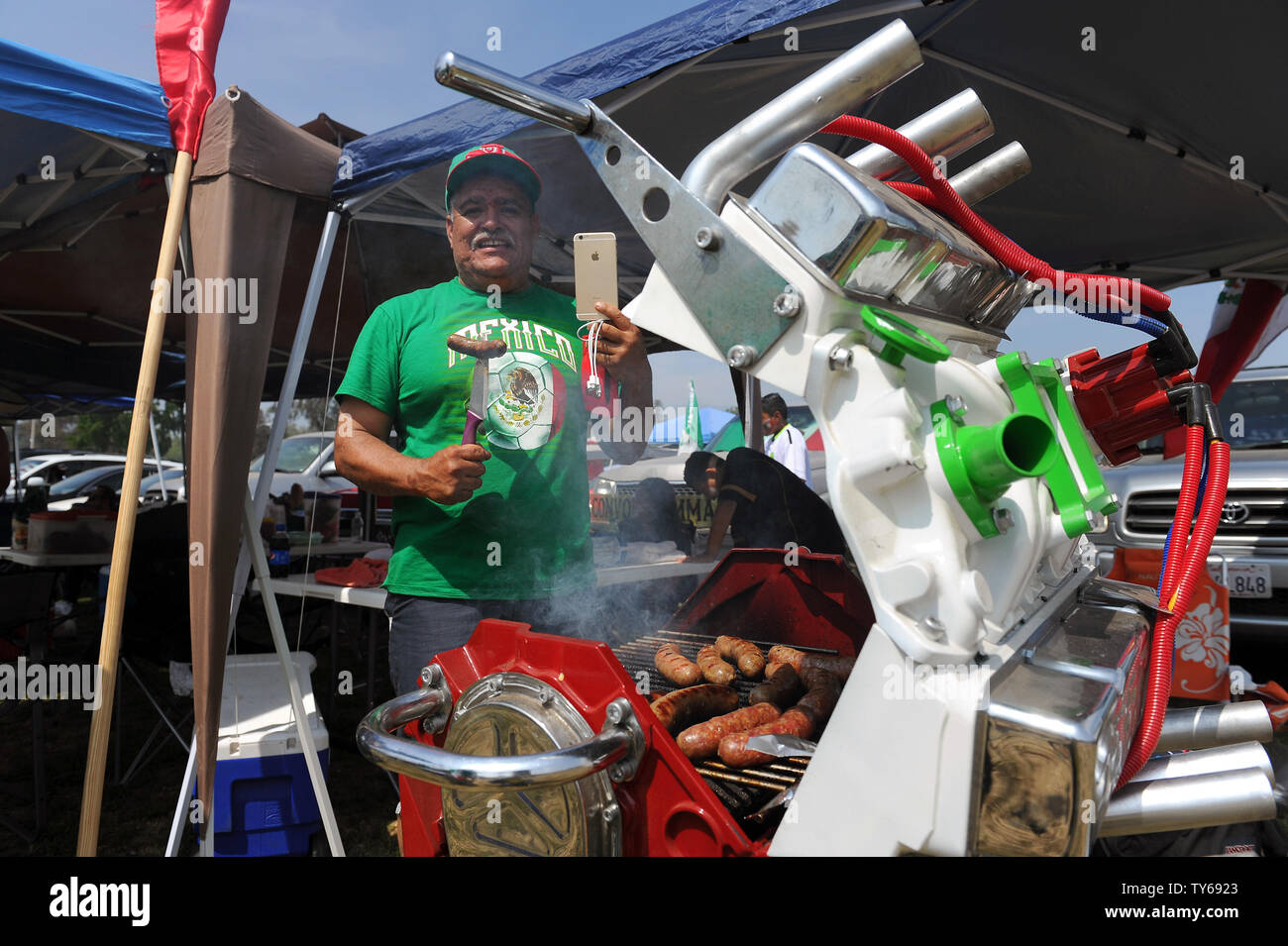 Salvador Solorzano grills sausages on a Chevy 357 engine barbecue ...