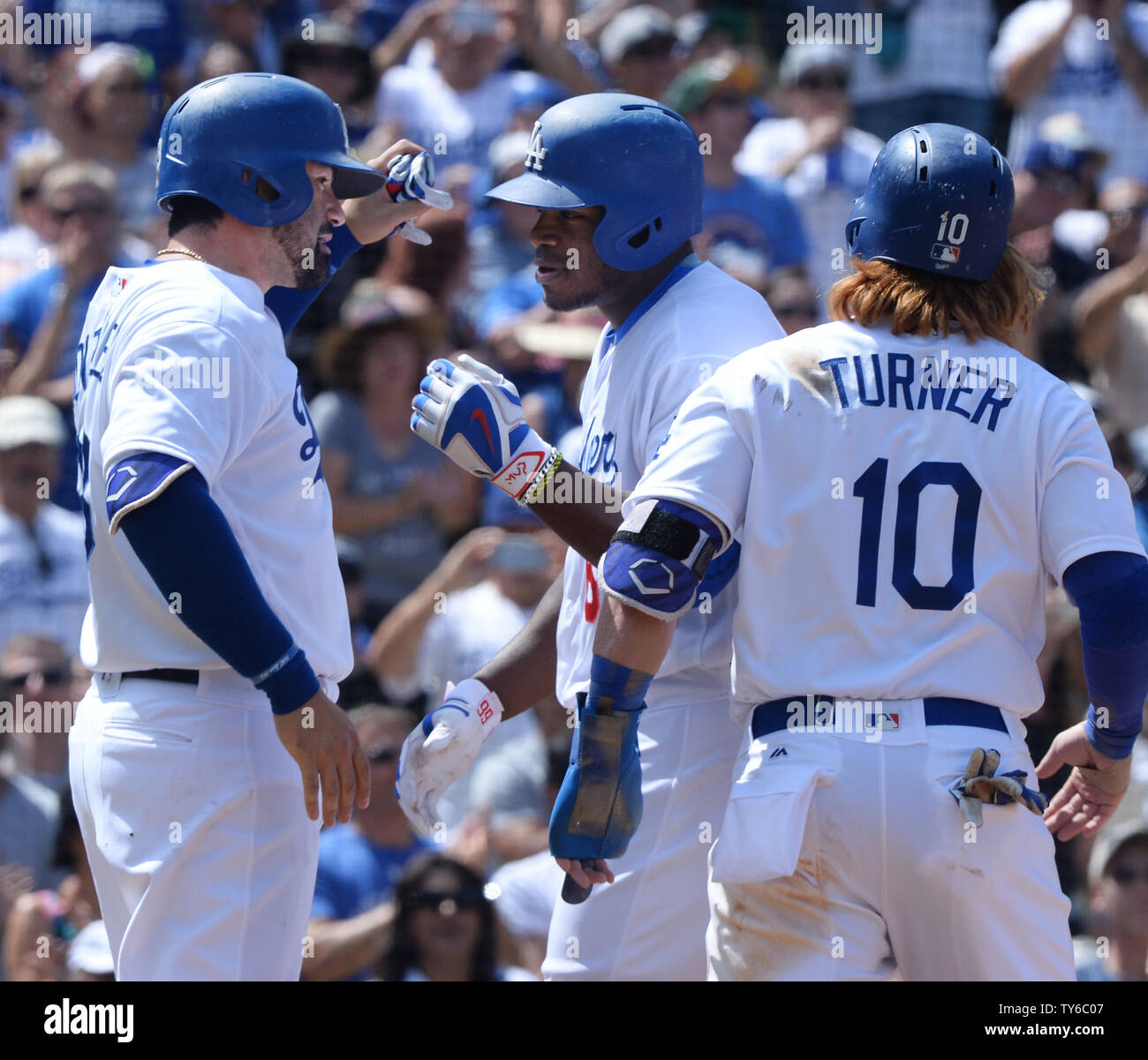 Los Angeles Dodgers' right fielder Yasiel Puig (C) is welcomed home by ...