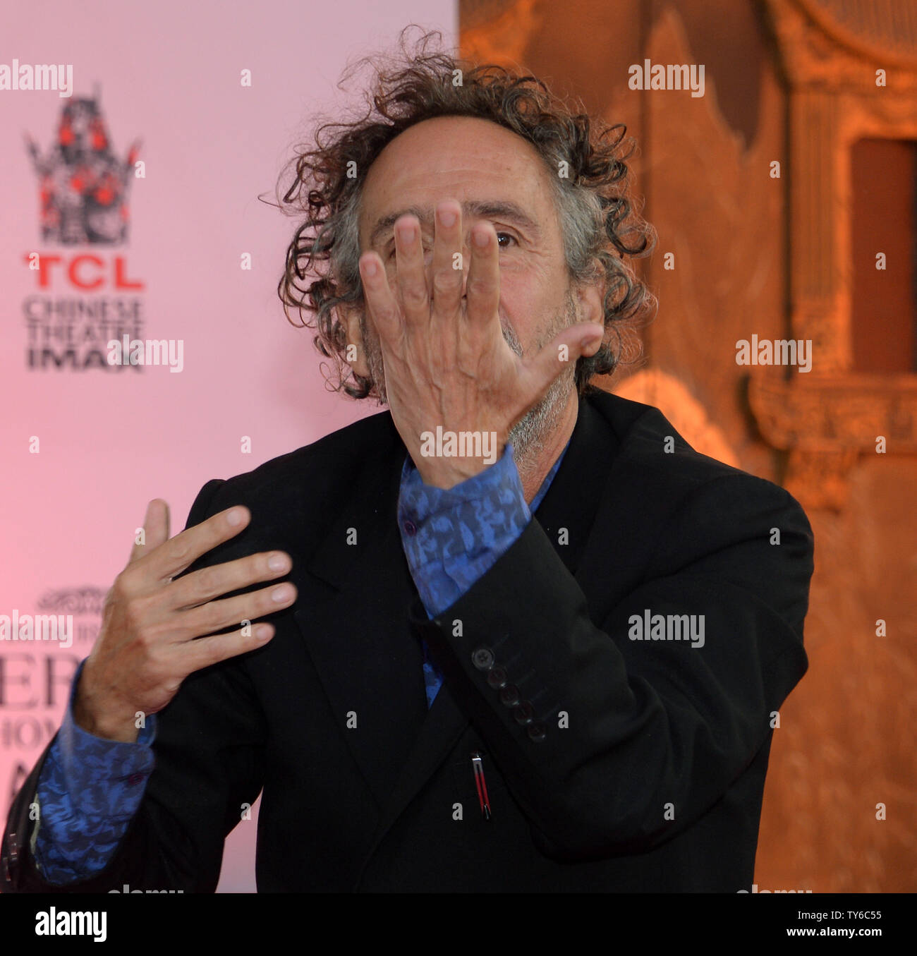 Director Tim Burton licks his cement-covered hands during a hand ...