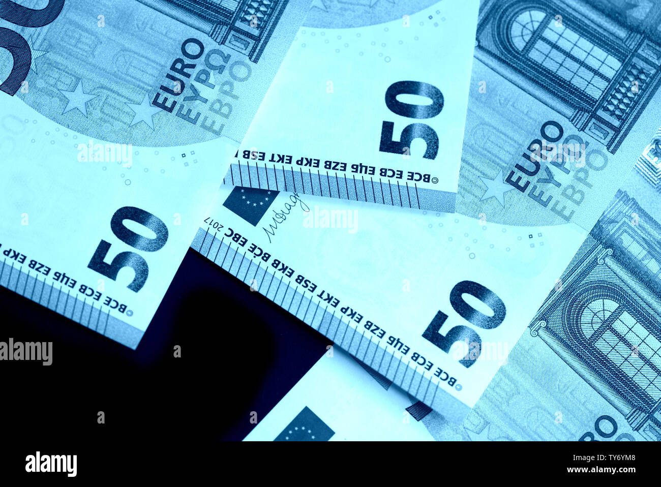 Fifty euro notes on a dark background close up. Blue color toned Stock ...