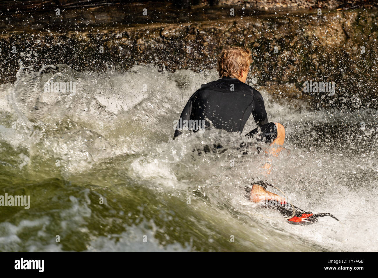 Man surfing in the waves of the Eisbach River in Munich. It forms a ...