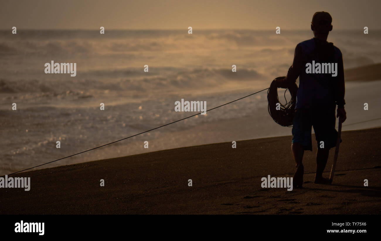 fisherman pulling nets from sea at sunset on sandy beach. Fisherman ...