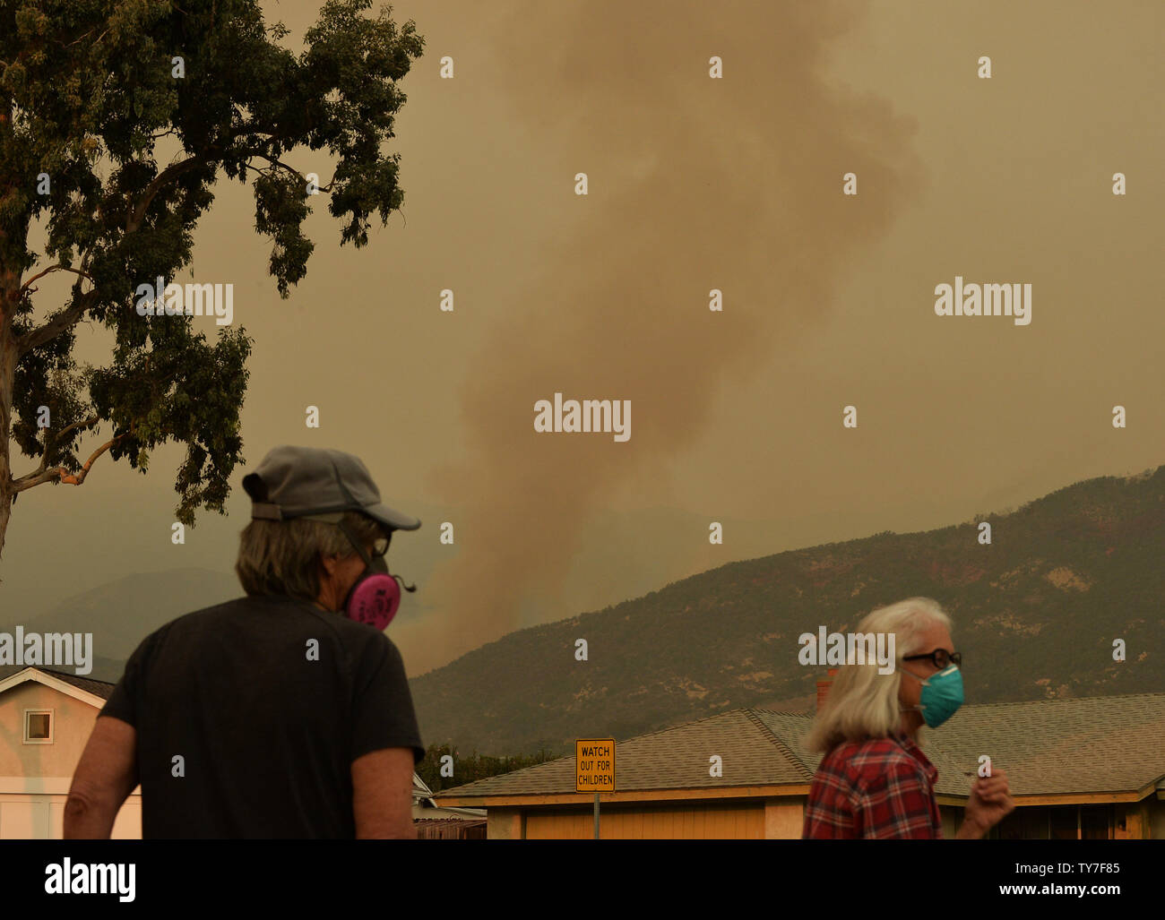 Local residents don breathing masks as they look at a structure fire ...