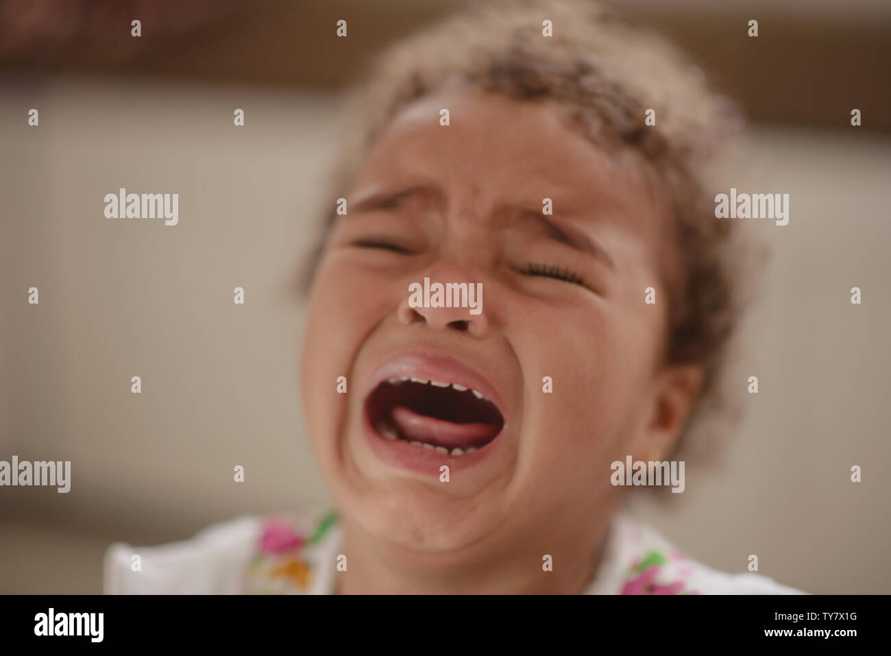 Beautiful sad little girl crying, on light background Stock Photo - Alamy