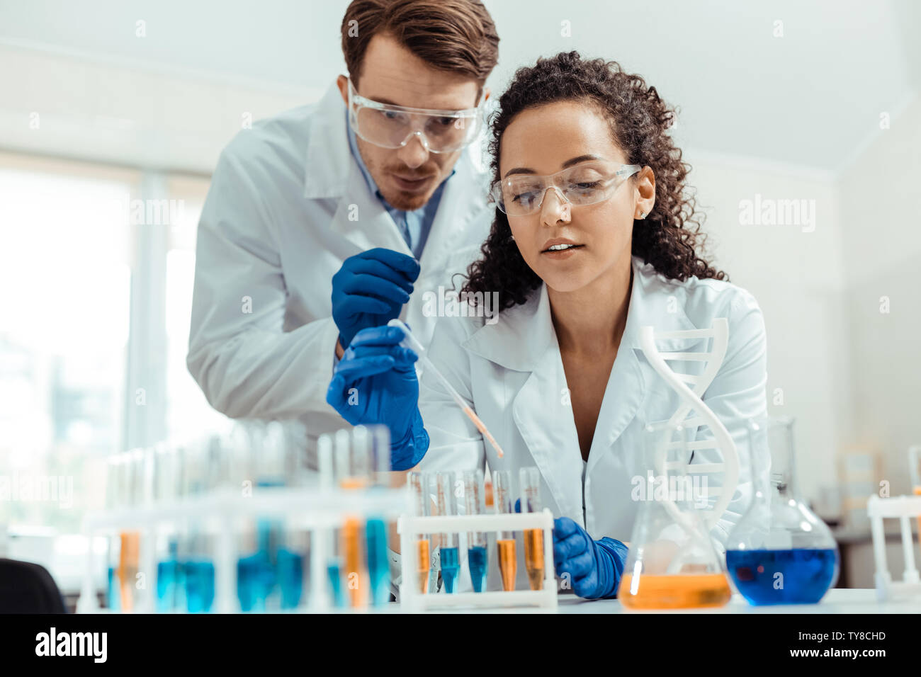 Nice young man helping his colleague with the research Stock Photo - Alamy