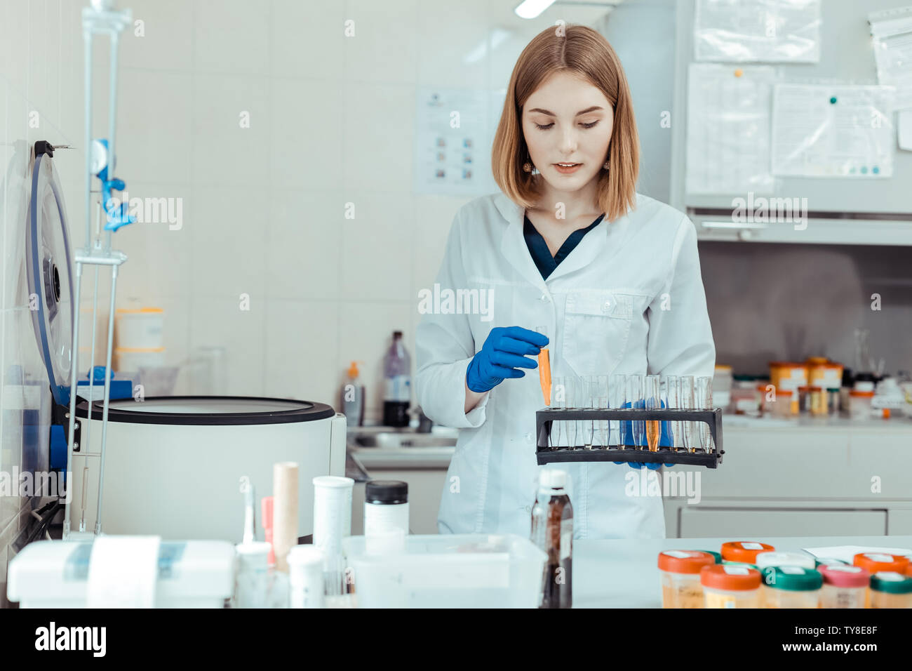 Intelligent young woman taking test tubes for examination Stock Photo ...