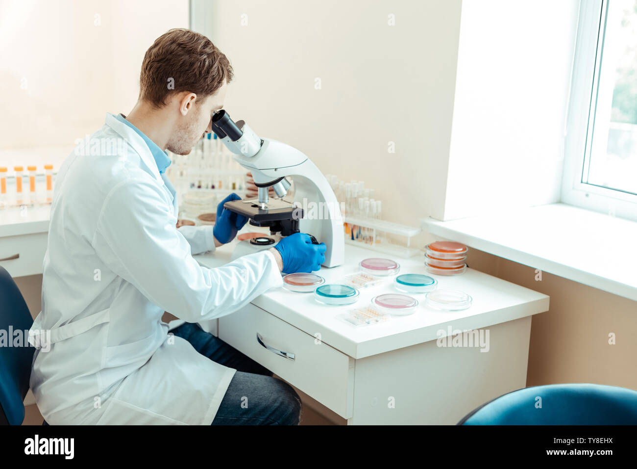 Handsome nice man sitting in front of the microscope Stock Photo - Alamy