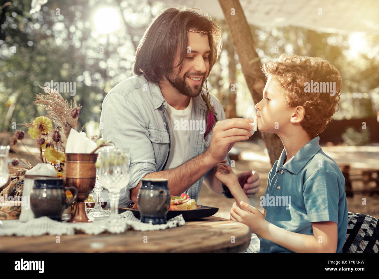 Nice long haired man sitting with his son Stock Photo - Alamy