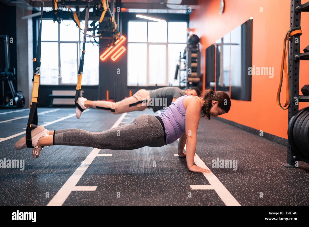 Overweight woman standing in plank with feet in TRX straps Stock Photo ...