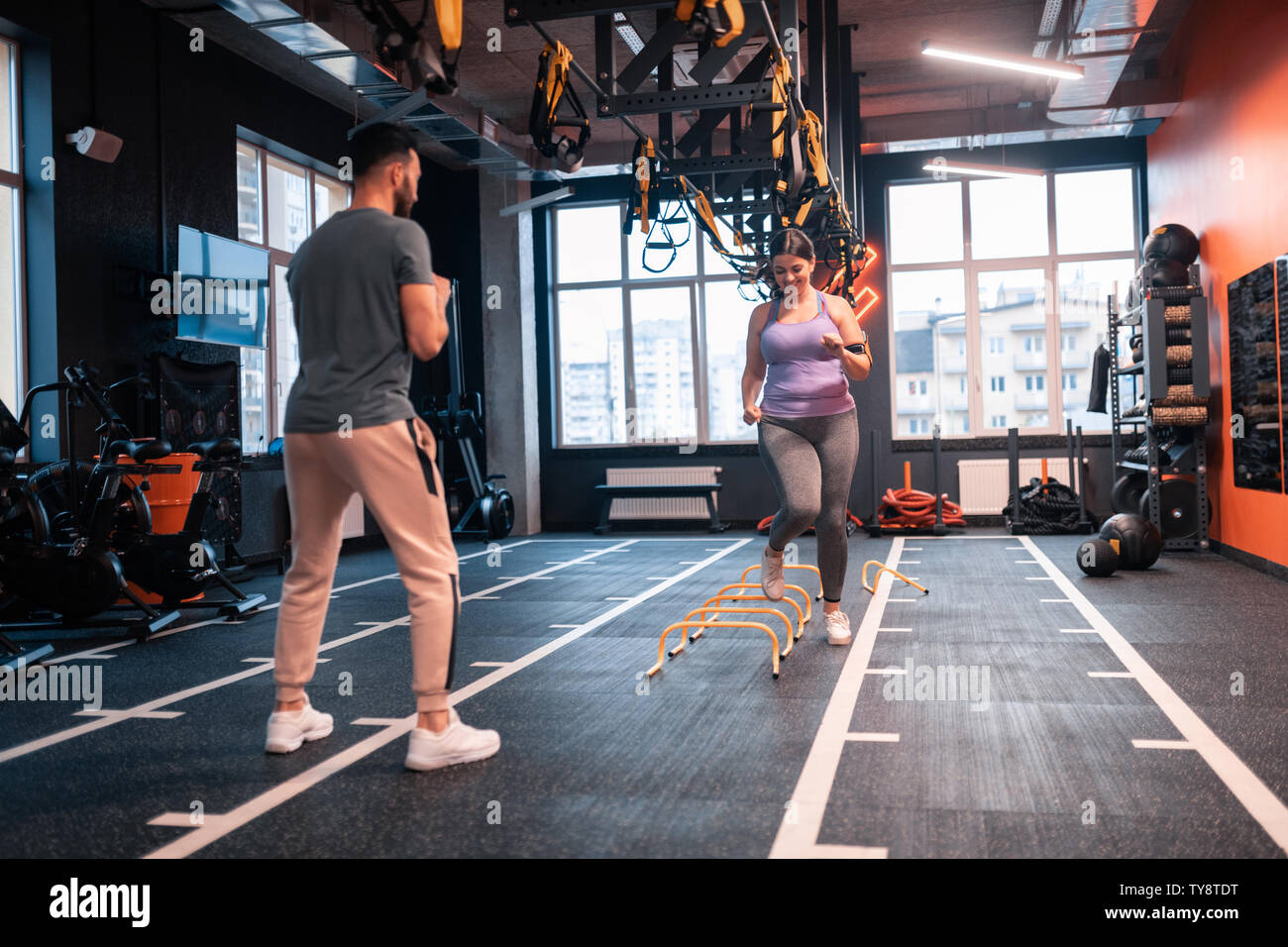 Overweight woman having obstacle race in gym with her trainer Stock ...