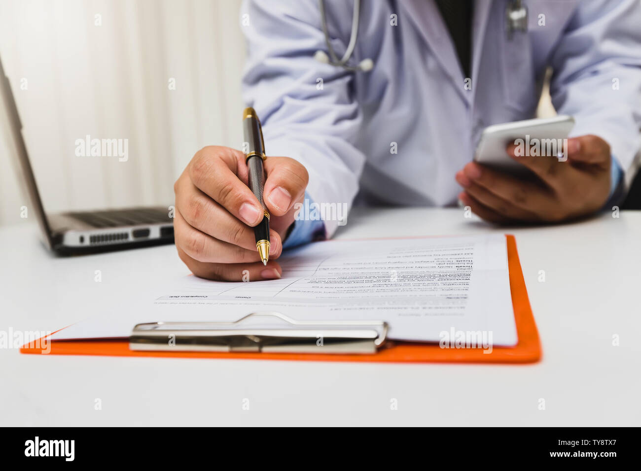 Doctor in gown uniform using a pen write on medical chart Stock Photo ...