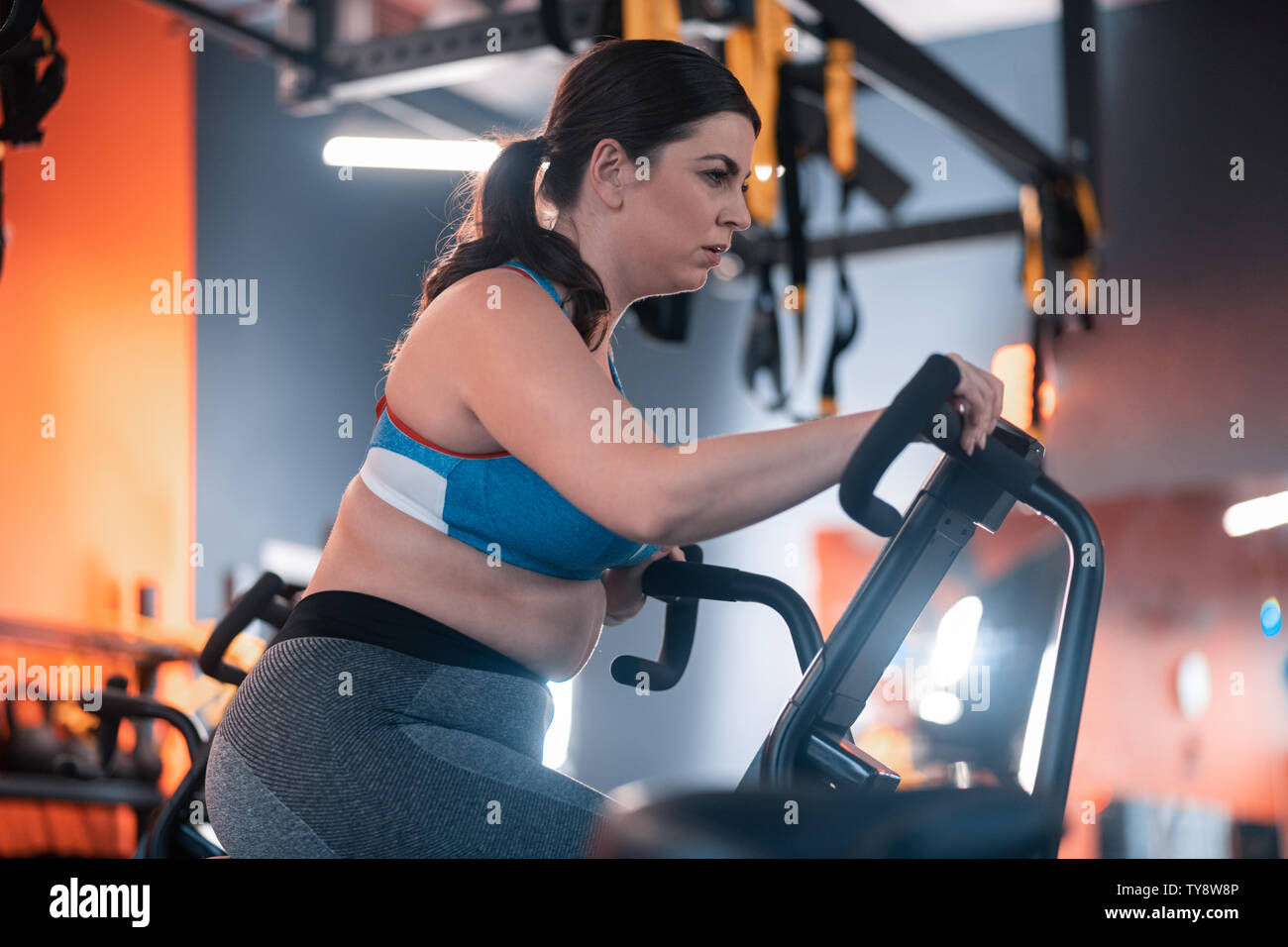 Plump woman cycling in gym feeling truly exhausted Stock Photo - Alamy