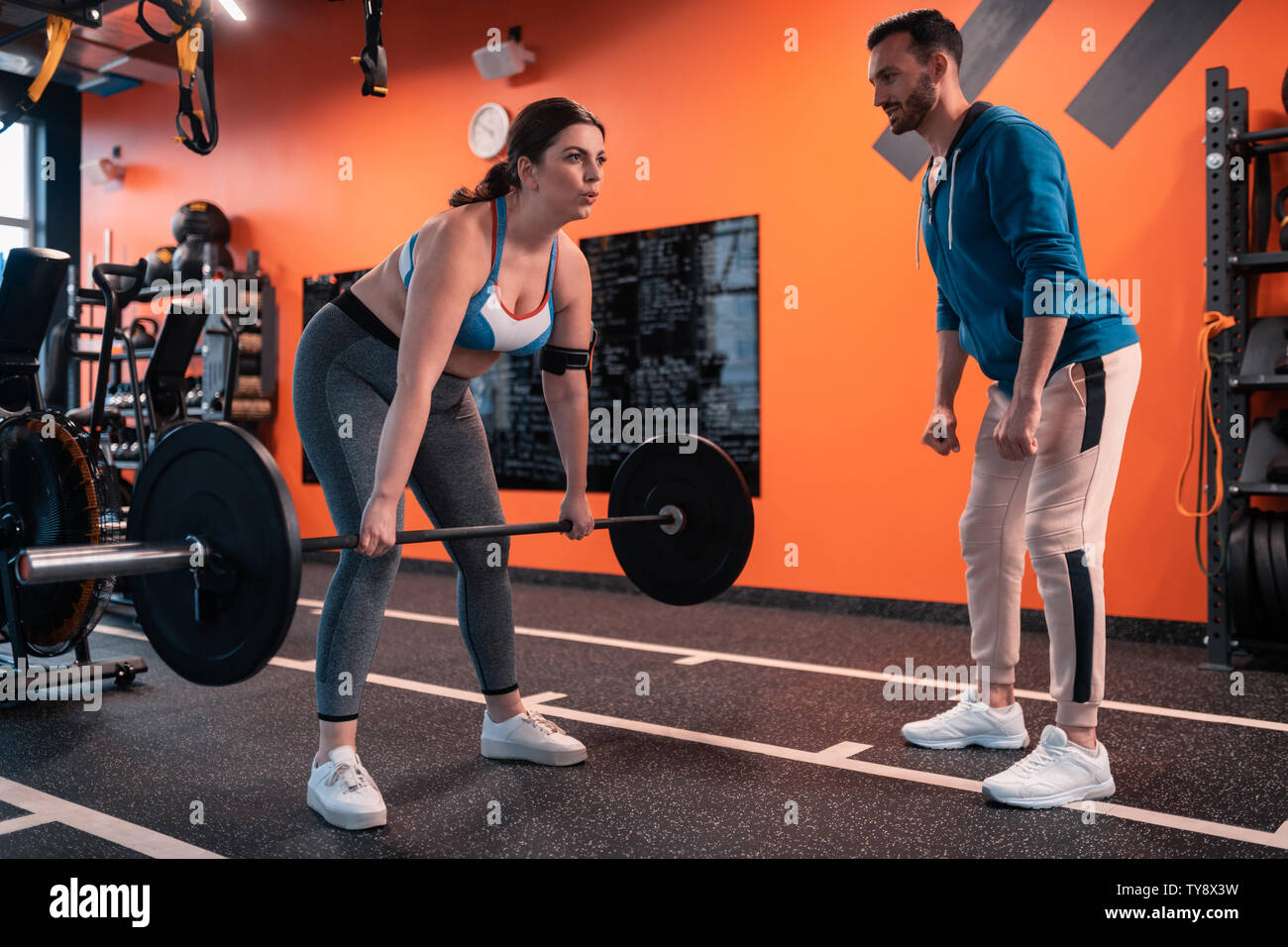 Overweight woman hardly breathing while lifting barbell Stock Photo - Alamy