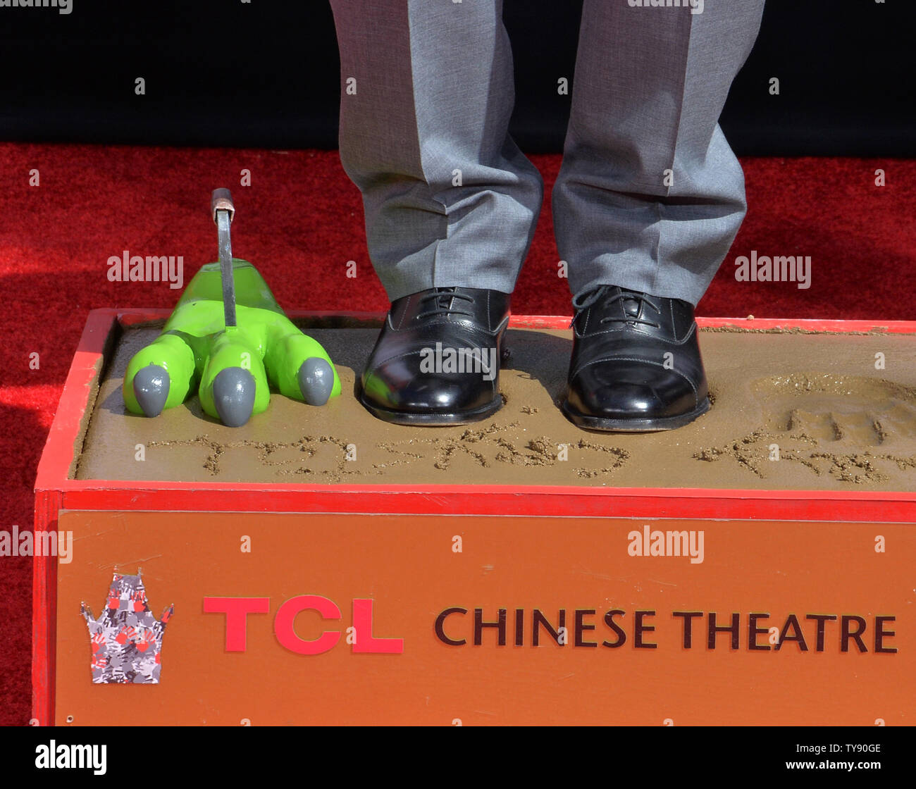 Actor and comedian Billy Crystal stands in wet cement with a prop from ...