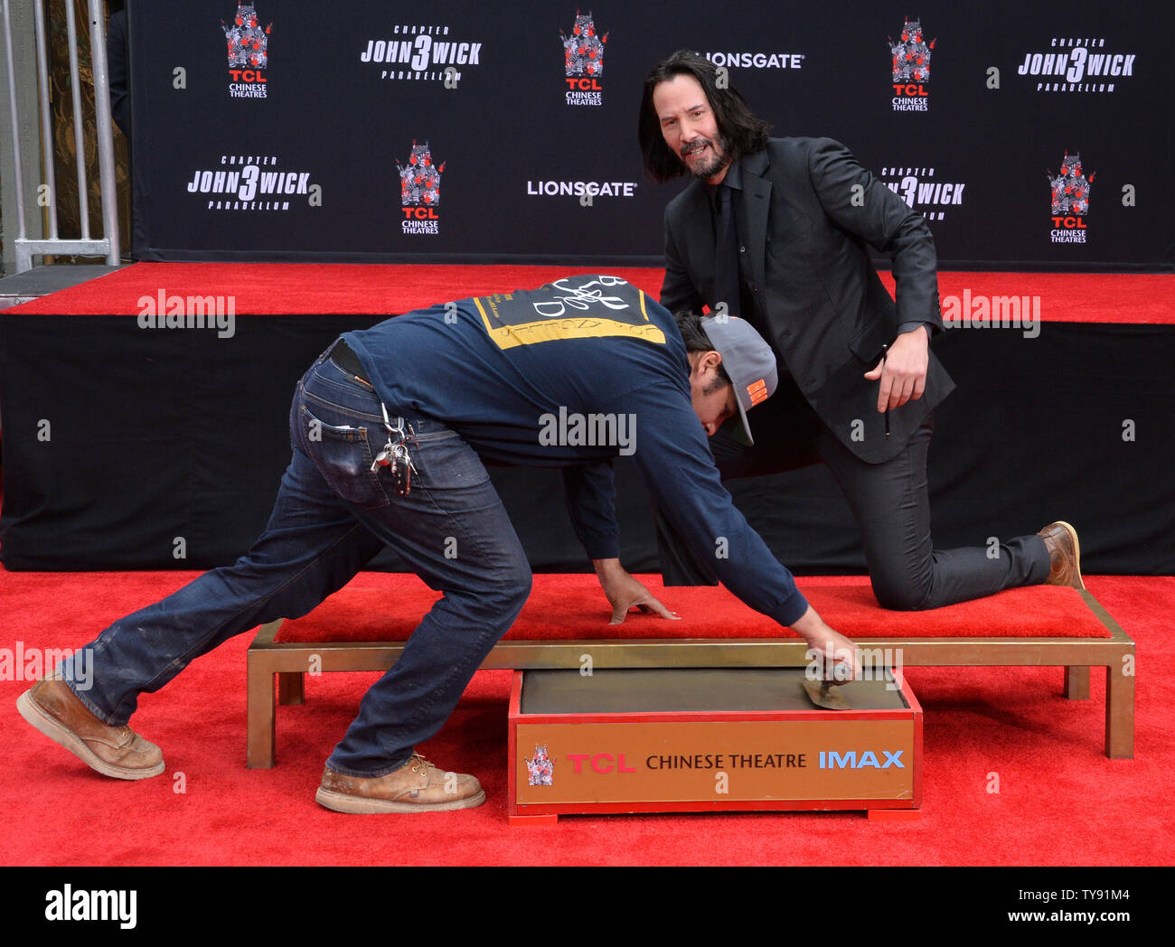 A worker gives actor Keanu Reeves a third chance to sign his name in ...