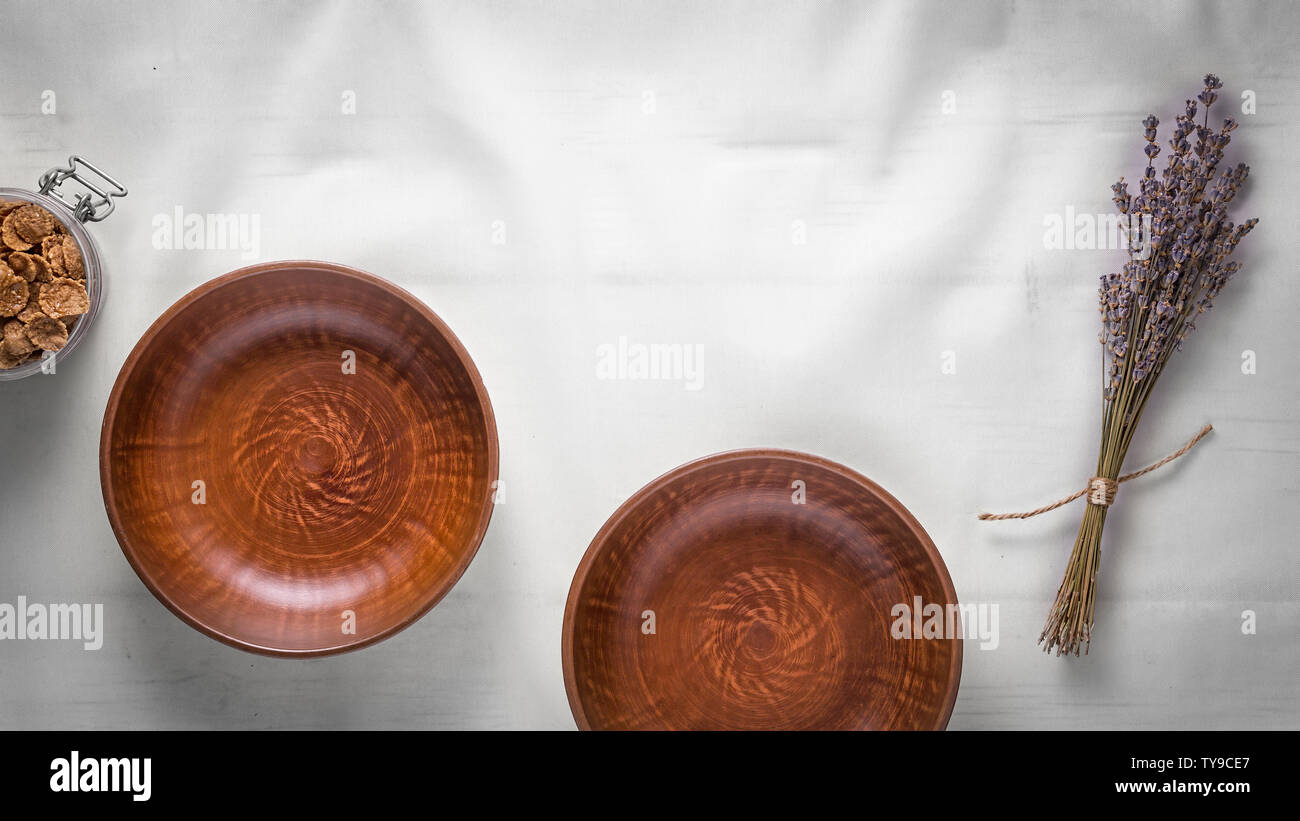 Clay bowls and cereal for breakfast on a kitchen table with a white ...