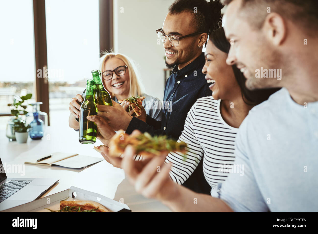 Diverse group of laughing businesspeople cheering with beers while ...