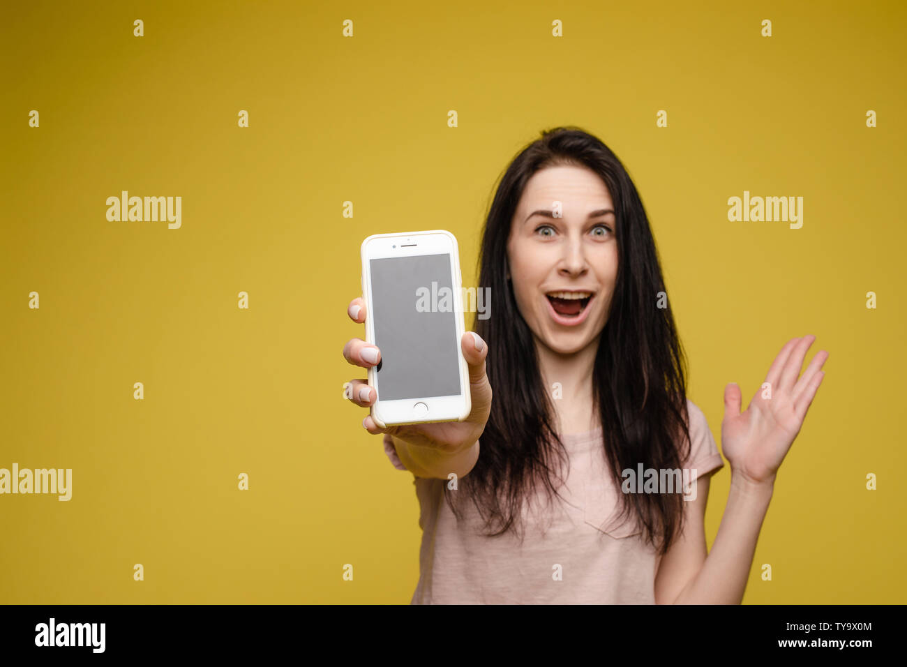 Girl showing mobile to the camera with shocked expression Stock Photo ...