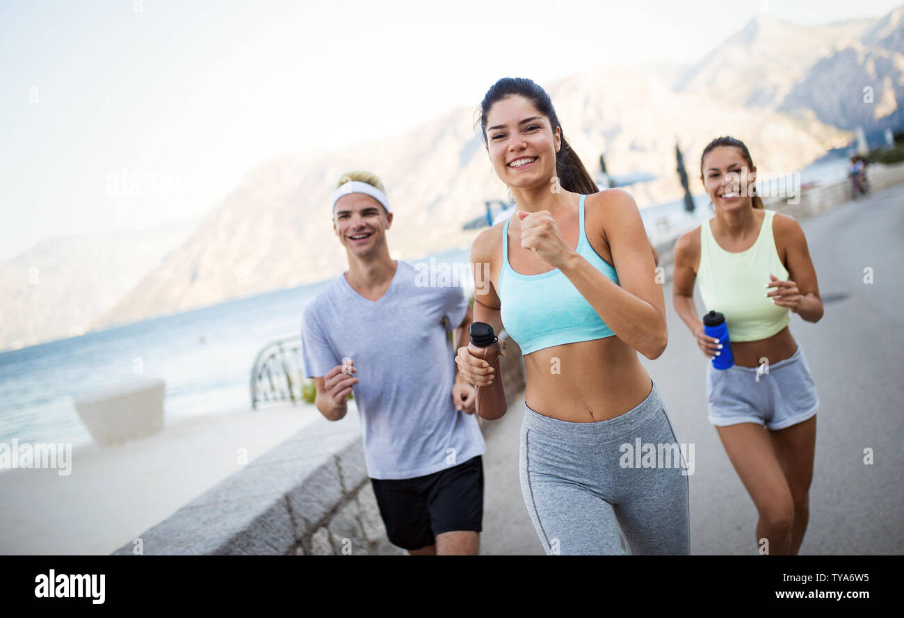 Happy fit people running and jogging together in summer sunny nature ...