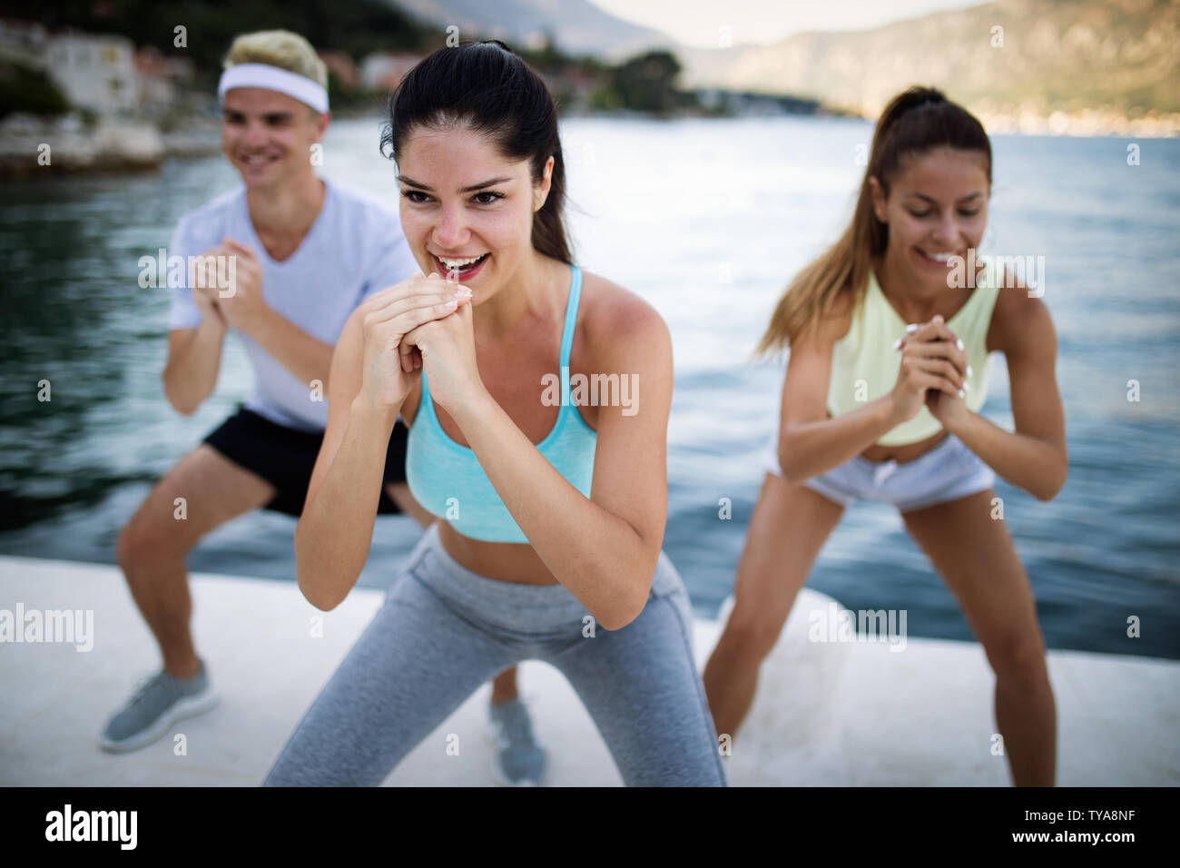 Fit group of happy people exercising outdoor. Smiling friends doing ...