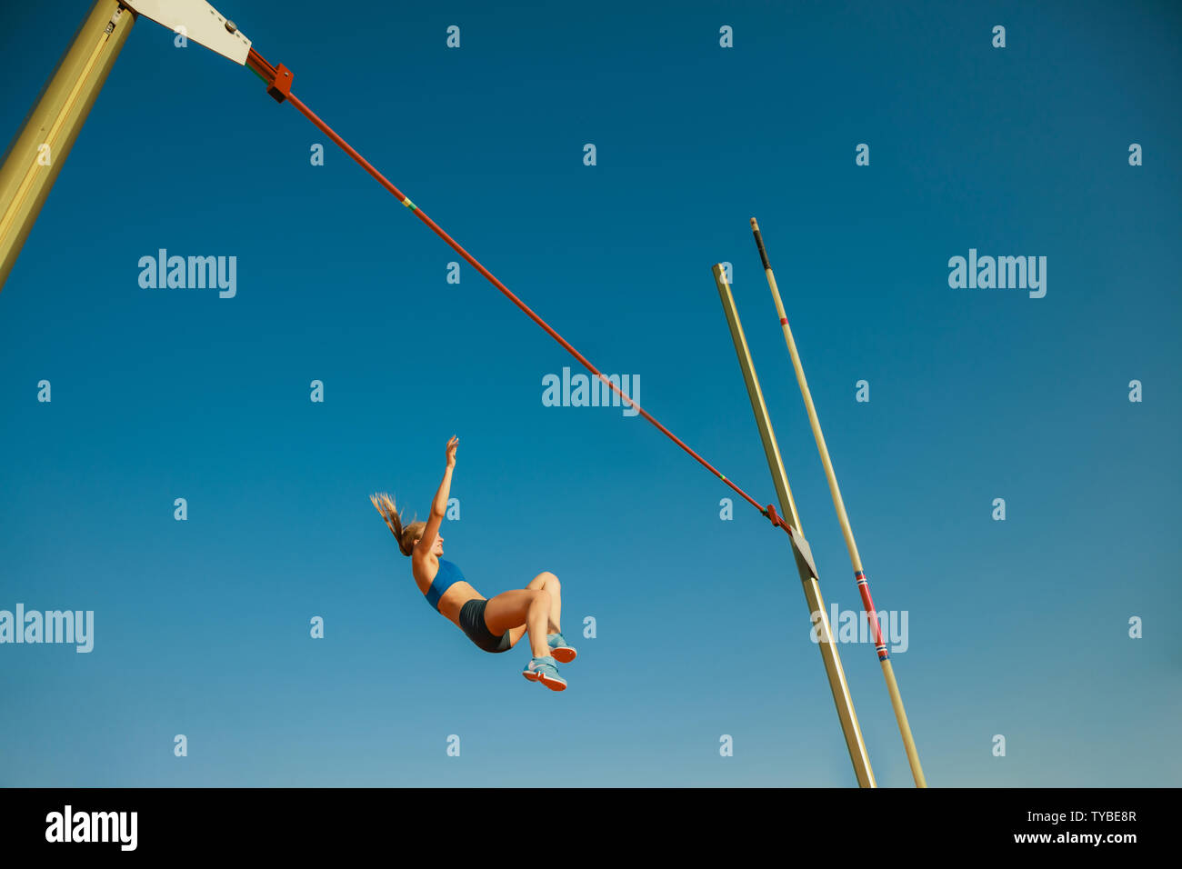 Professional female high jumper training at the stadium in sunny day ...