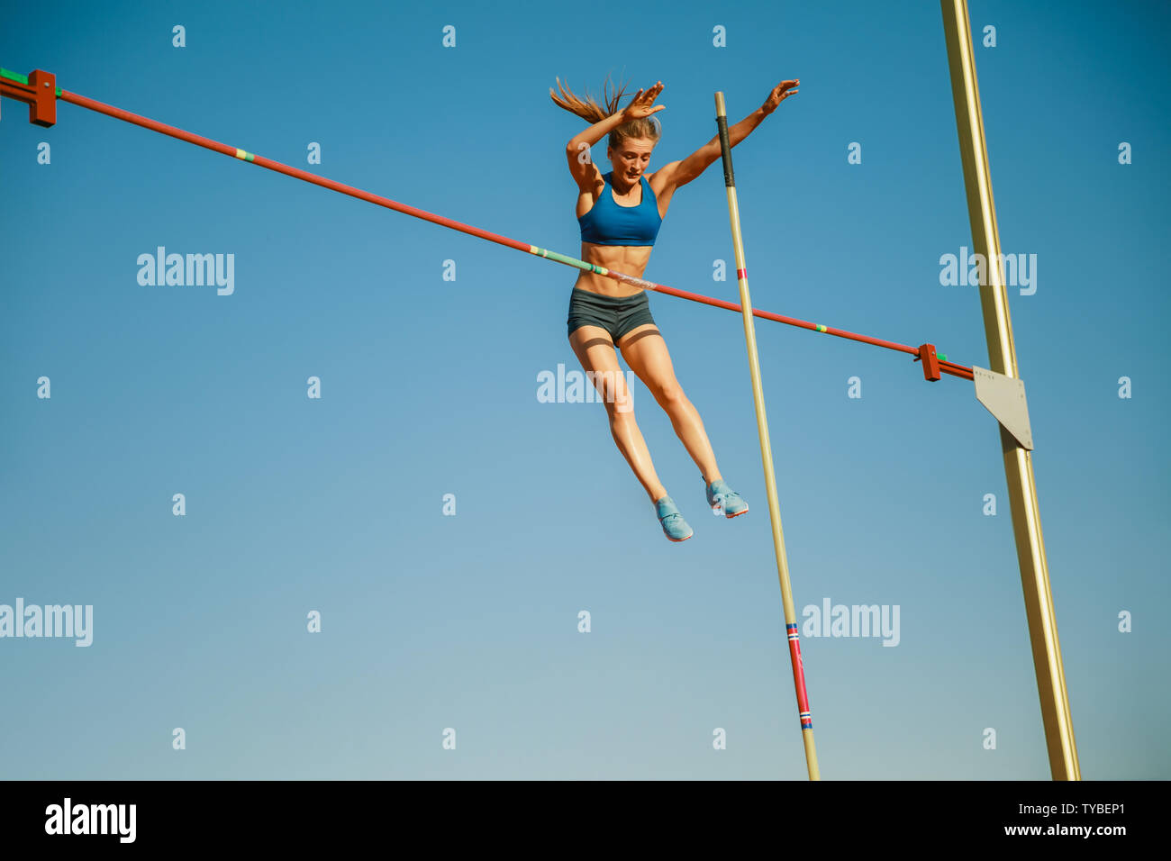 Professional female high jumper training at the stadium in sunny day ...