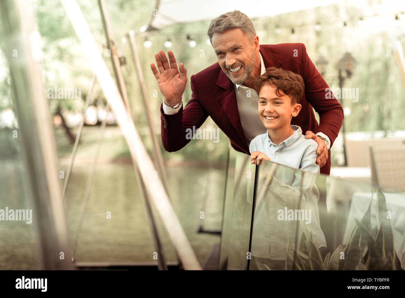 Father and son waving seeing mother coming to restaurant Stock Photo ...